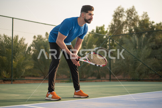 A sports racket, a young Saudi Arab Gulf man wearing sports clothes ...
