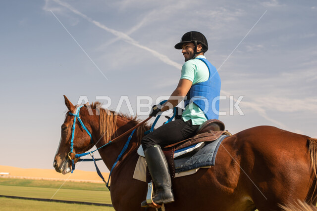 A picture from the back of a young Saudi Arabian Gulf man riding a ...