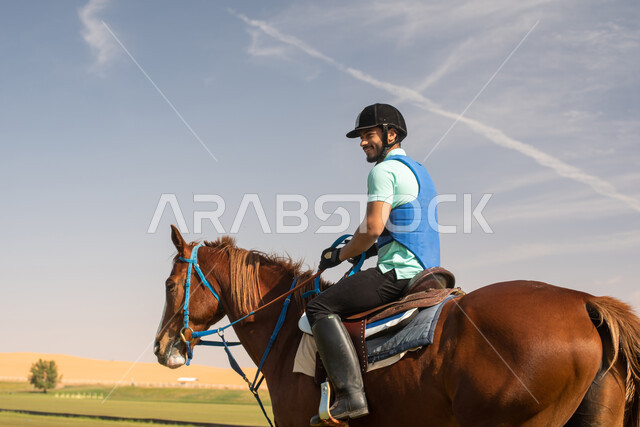 A picture from the back of a young Saudi Arabian Gulf man riding a ...