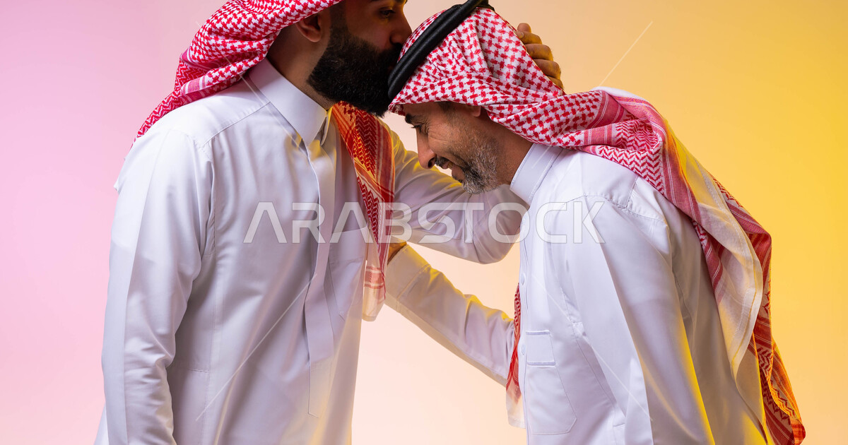 Portrait of a young Saudi Arabian Gulf man kissing his father's head ...