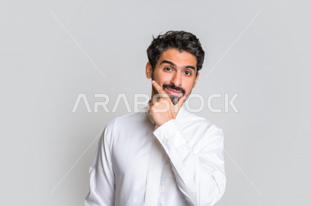 Portrait of a Saudi Gulf man in traditional dress, making facial and ...