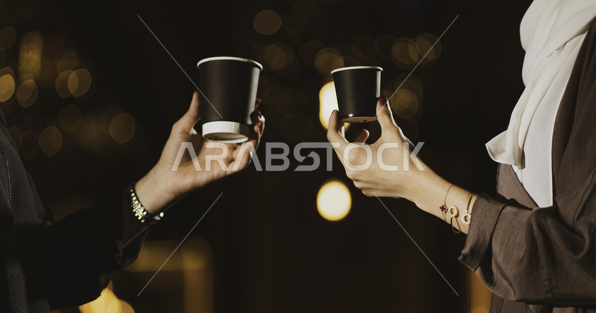 A close-up of two women's hands carrying a cup of coffee, ordering ...