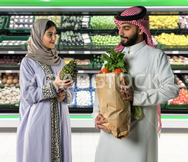 A Gulf Saudi Arab couple in the fruit section of the supermarket, a man ...