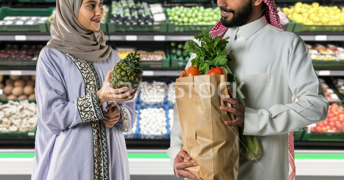 A Gulf Saudi Arab couple in the fruit section of the supermarket, a man ...