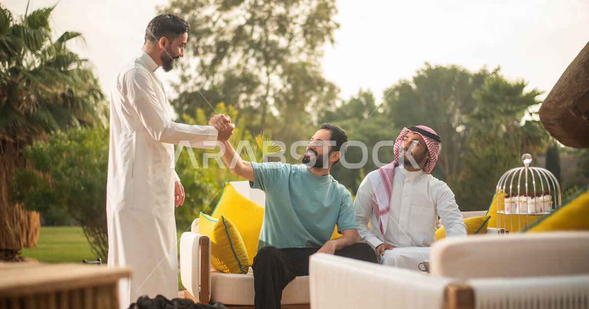 Greetings and peace, two Saudi Arabian Gulf men shaking hands happily ...