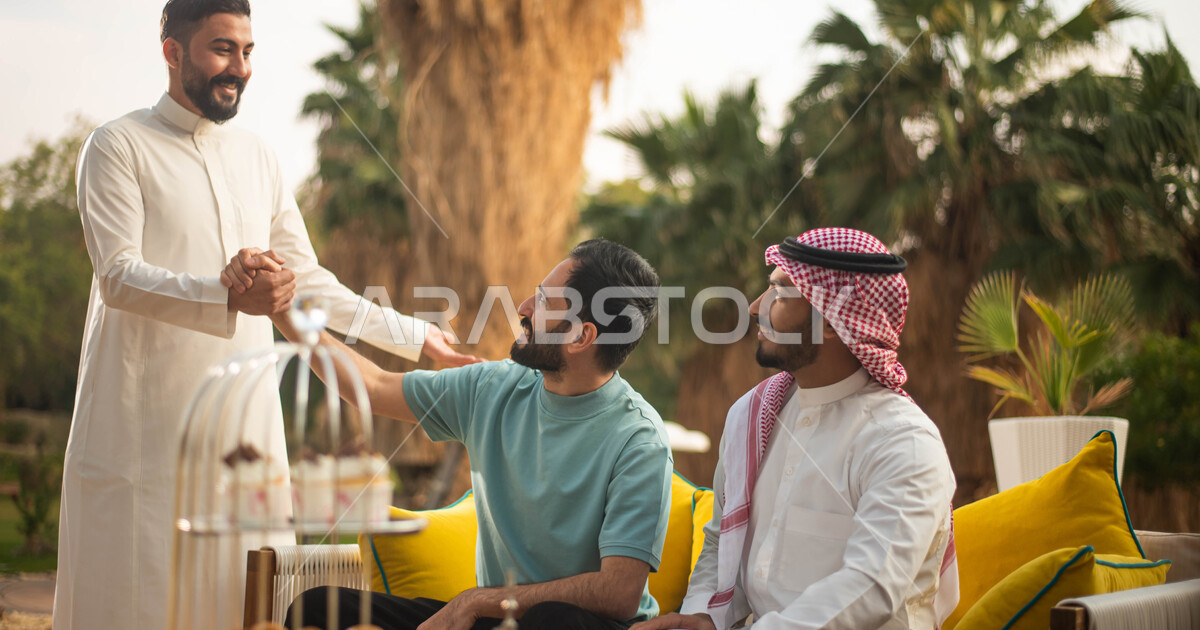 Greetings and peace, two Saudi Arabian Gulf men shaking hands happily ...