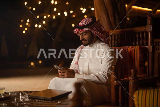 Carrying out work tasks, a Saudi Arabian Gulf man wearing traditional ...
