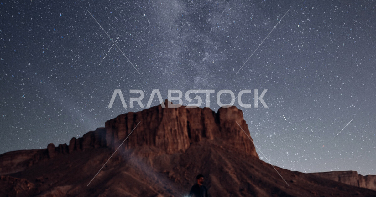 A man holding a light bulb standing in a desert land in front of the ...