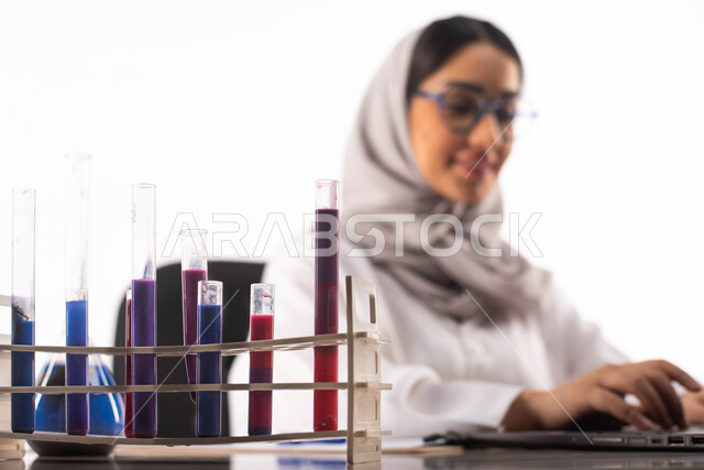 Using a laptop computer, research and development, sitting in a chemistry lab, a portrait of a ...