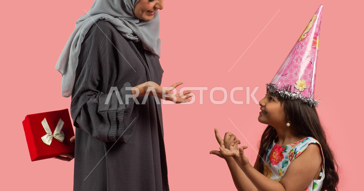 أم تفاجئ إبنتها بعلبة هدايا حمراء، إيماءات وجه ويدين تدل على الدهشة