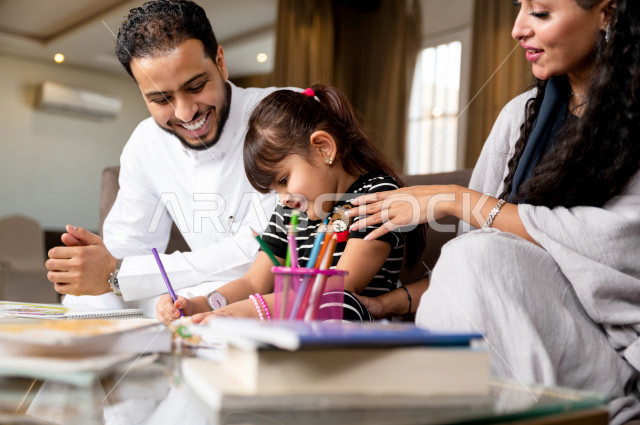 A Saudi Gulf student studying at home with her father and mother ...