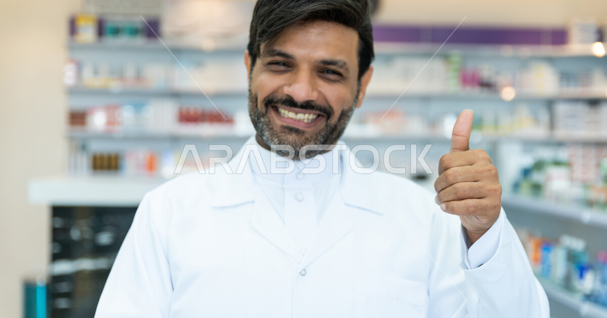 A smiling Saudi Arabian Gulf Arab pharmacist raises his thumb inside ...