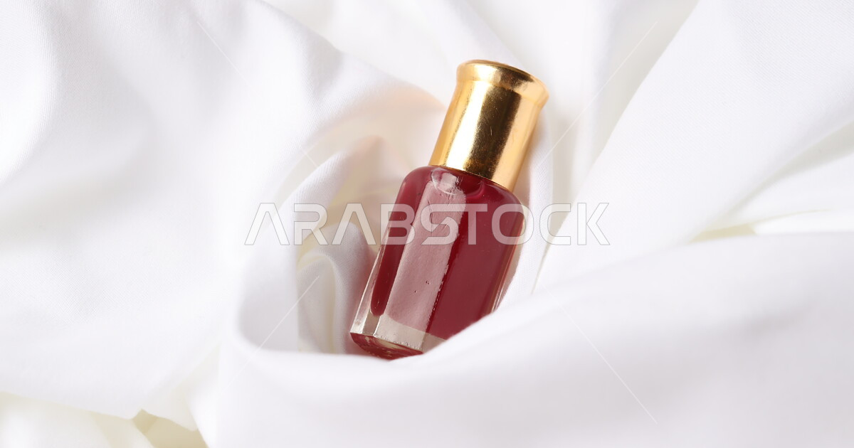 A glass tola of the original Oud oil on a piece of white silk, perfume ...
