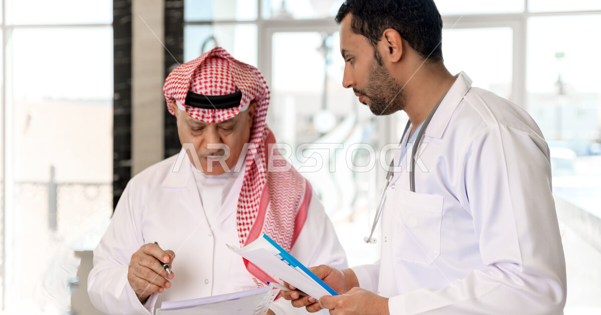 Two Gulf Arab and Saudi doctors working inside the hospital, exchanging ...