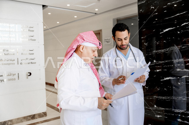 Two Gulf Arab and Saudi doctors working inside the hospital, exchanging ...
