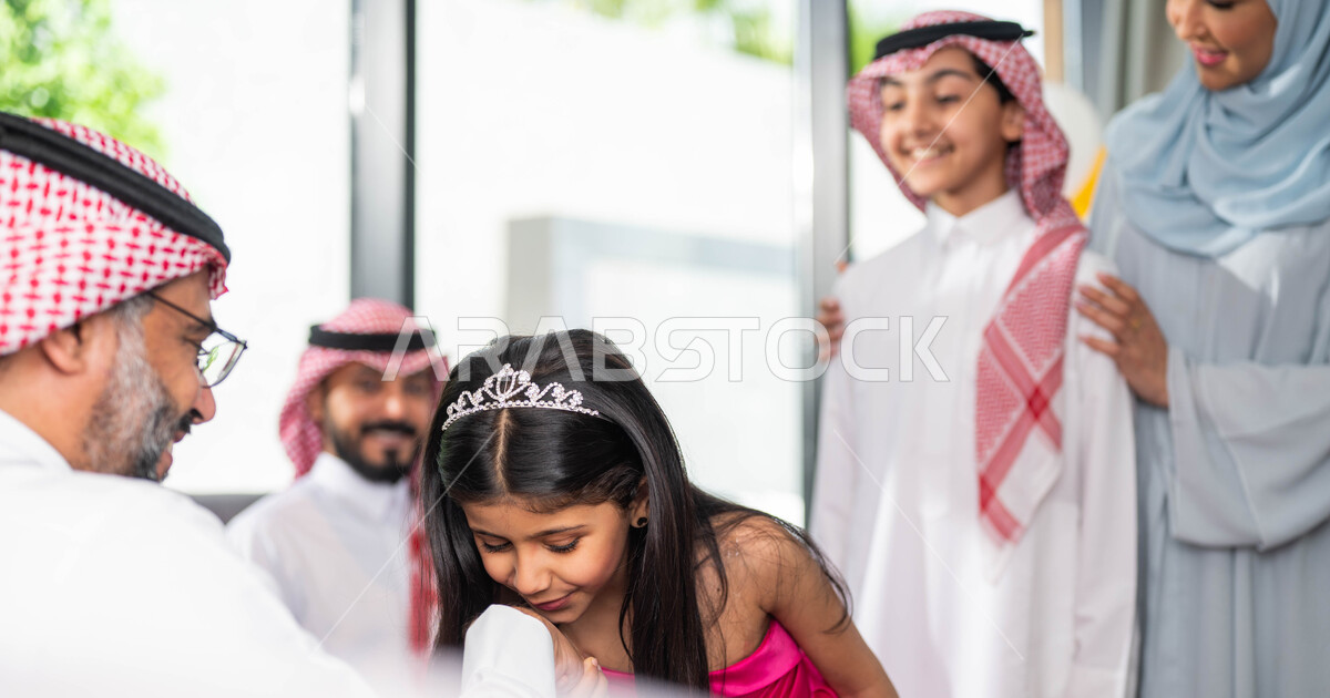 Respect and appreciation for parents, a Saudi Arabian Gulf girl kissing her grandfather's hand ...