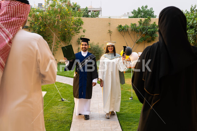 A happy Saudi family, a male and female university graduate wearing ...