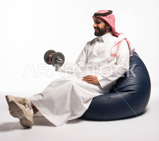 Bodybuilding, a portrait of a Saudi Arabian Gulf man sitting on a chair ...