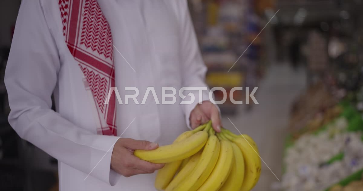 A Saudi Arabian Gulf man shopping for bananas from the fruit section ...