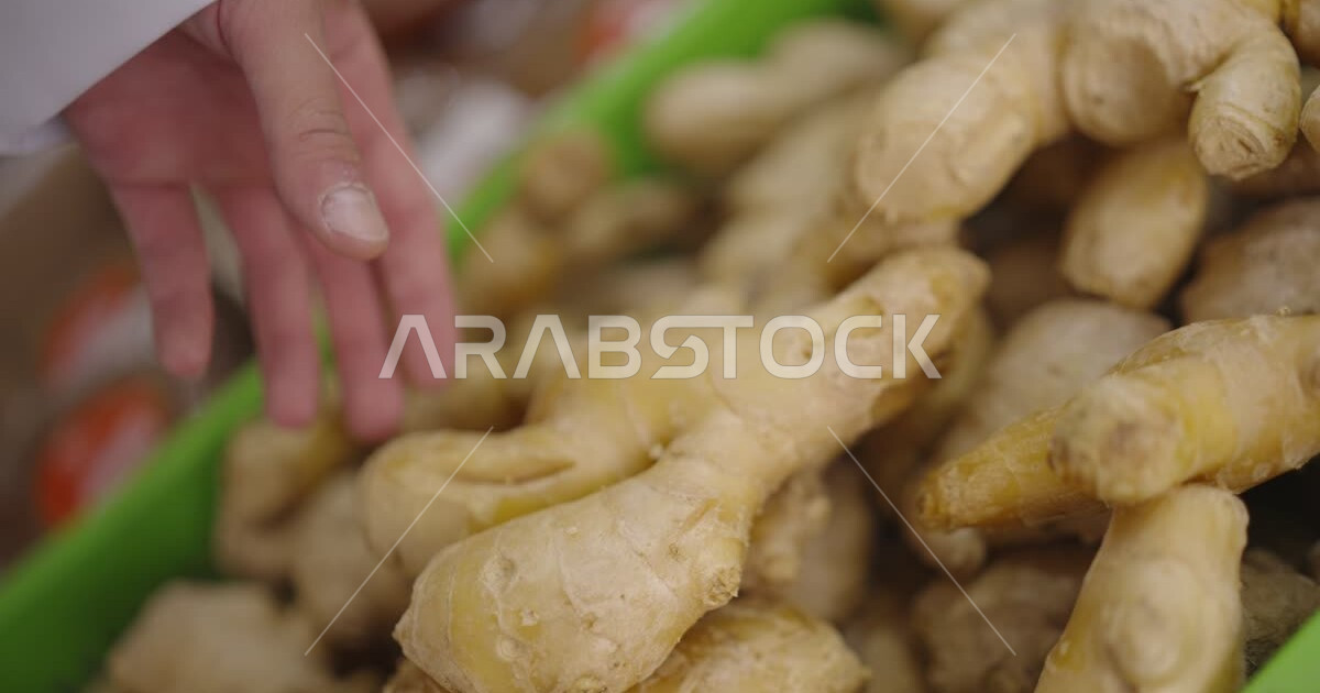 Close-up of a Saudi Arabian Gulf man shopping for ginger, vegetables ...