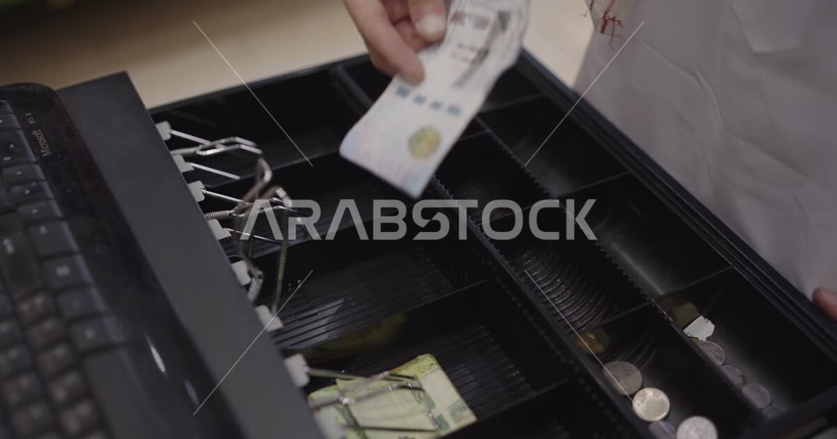 A Saudi Gulf Arab man puts money in the account drawer, accounting at ...
