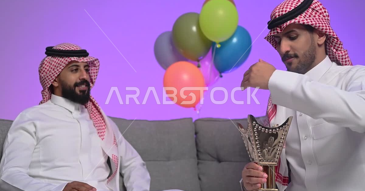 Two Saudi Arabian Gulf men wearing traditional Saudi dress and using ...