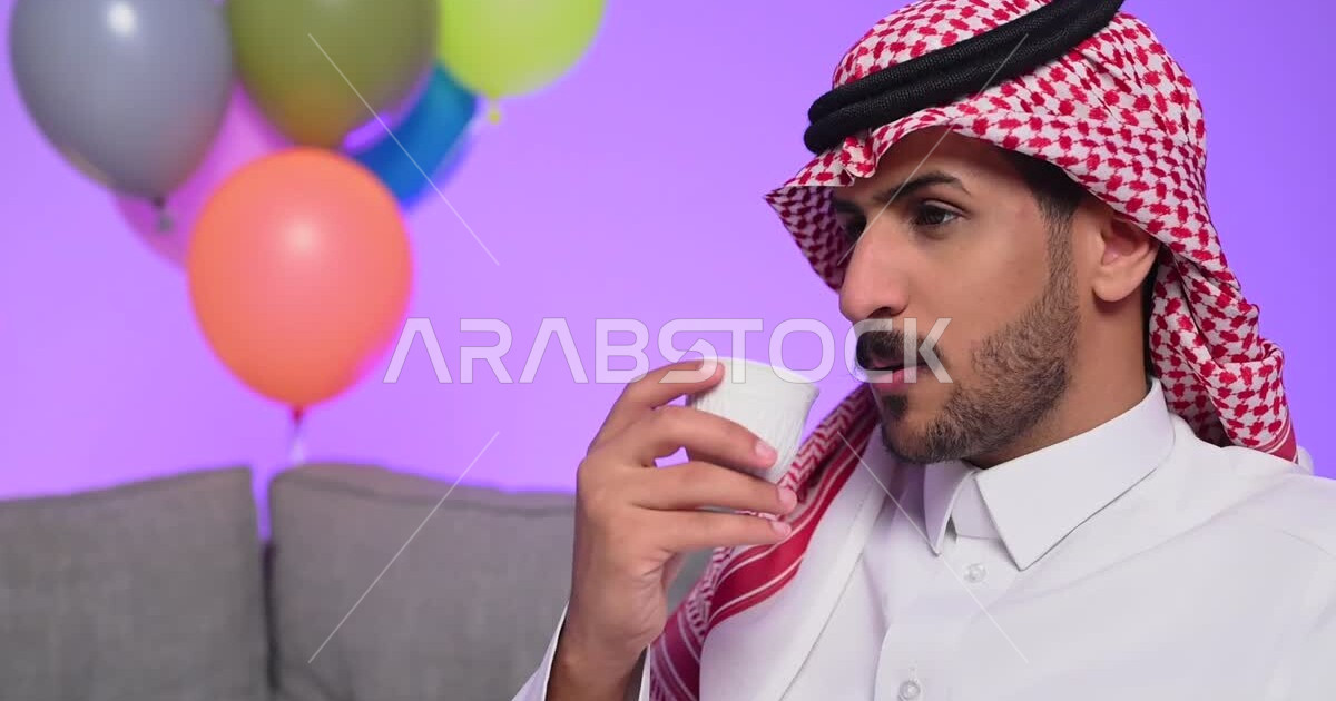 A Saudi Arabian Gulf man wearing traditional Saudi dress and drinking ...