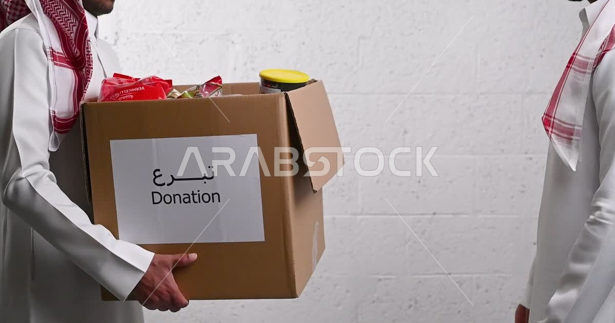 Close-up of a Saudi Gulf man donating a food parcel, two Saudi men ...