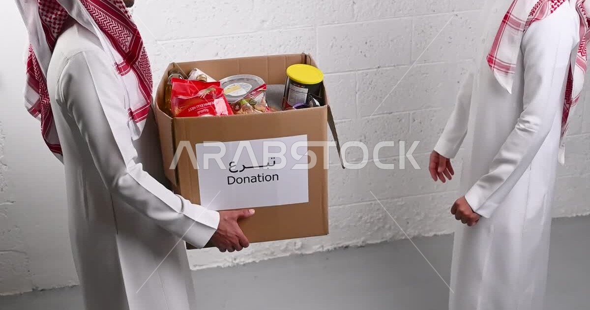 Close-up of a Saudi Arabian Gulf man donating a food parcel, two Saudi ...