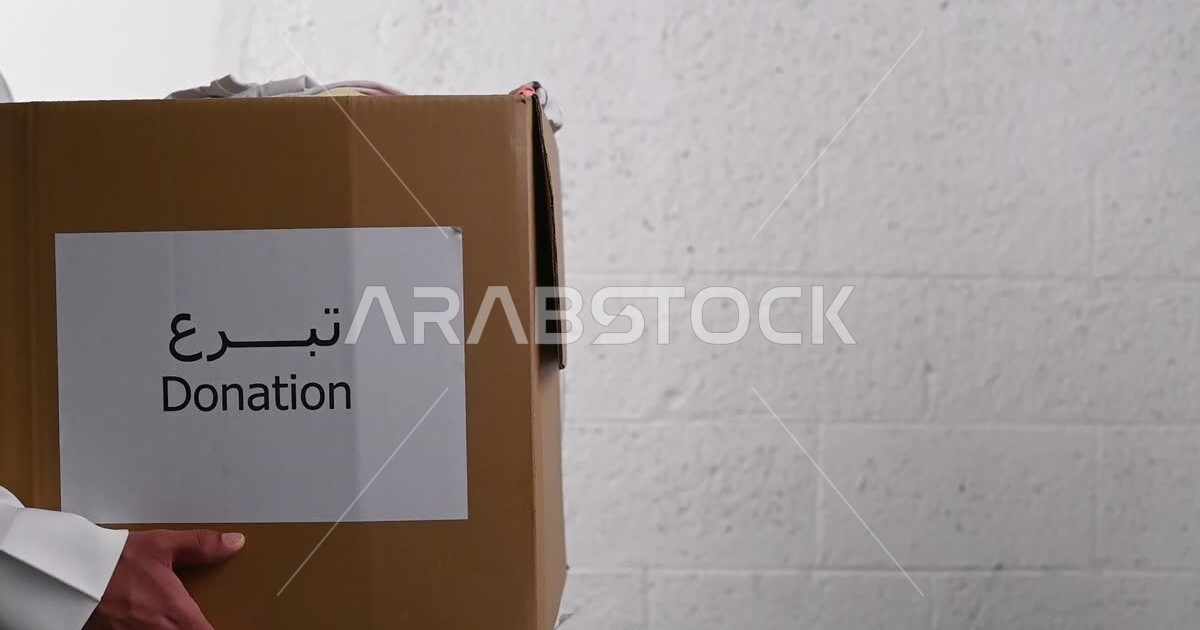 Close-up of a Saudi Arab Gulf man donating a box of clothes, two Saudi ...