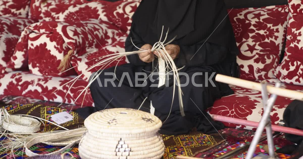 Close-up of a Saudi Arabian Gulf woman braiding wicker palms ...