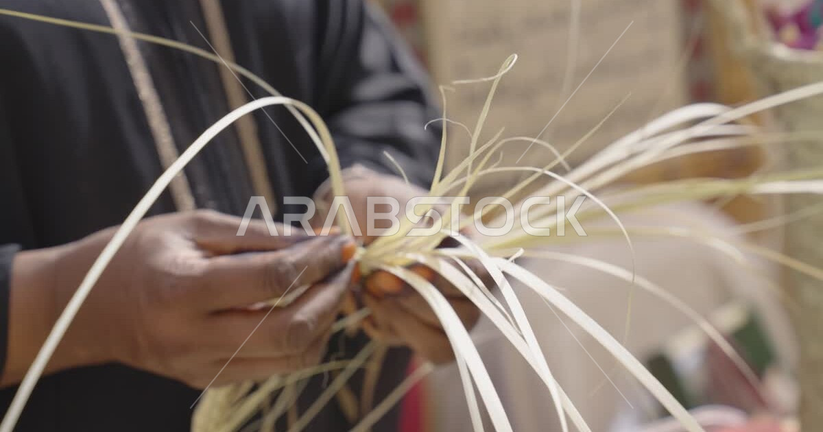 Close-up of a Saudi Arab Gulf woman making and braiding wicker palms ...