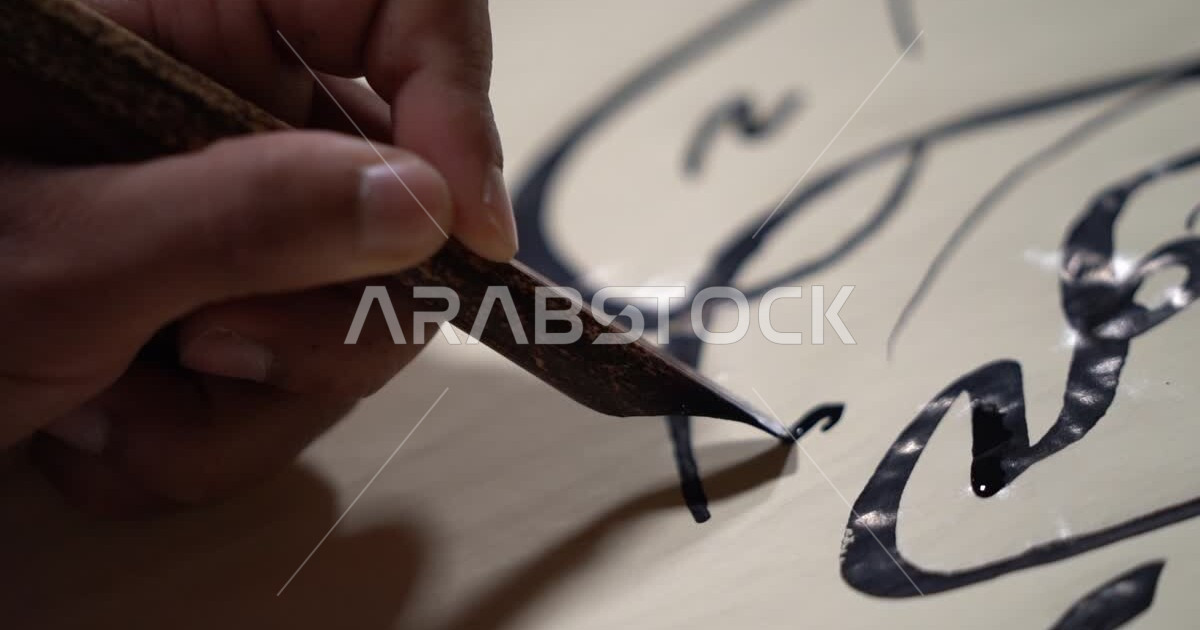 A close-up of a Saudi Arabian Gulf calligrapher writing a traditional ...
