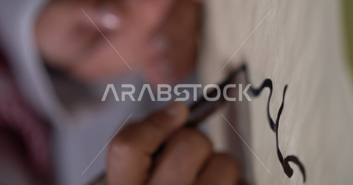 A man sketches Arabic words, a close-up of a Saudi Arabian Gulf ...