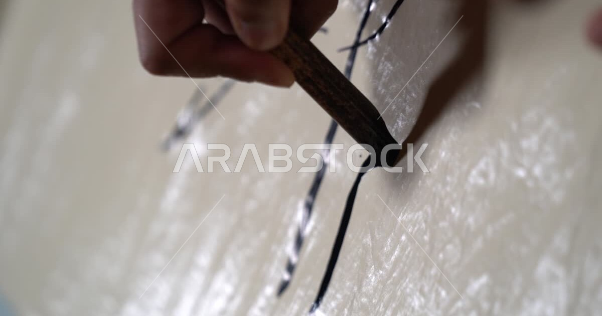 A man writing a traditional Arabic cursive, a close-up of a Saudi ...