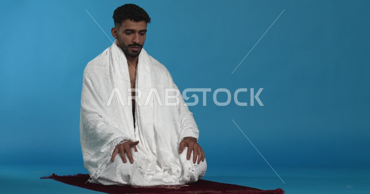 Performing the obligatory prayer, a Saudi Gulf Muslim young man wearing ...
