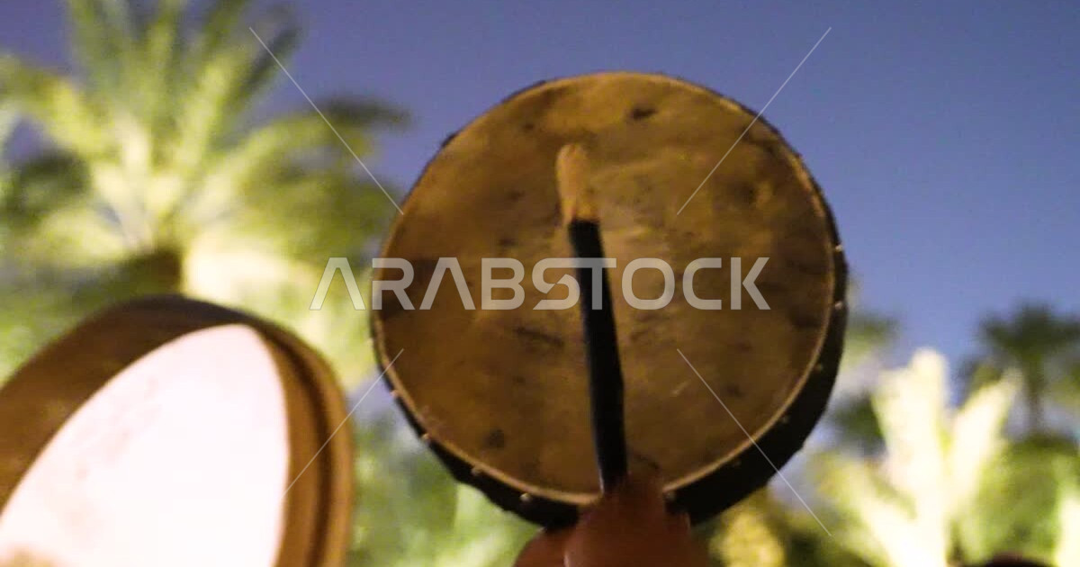 Close-up of a man's hand using a stick to beat drums, Saudi Al-Ardah Al ...
