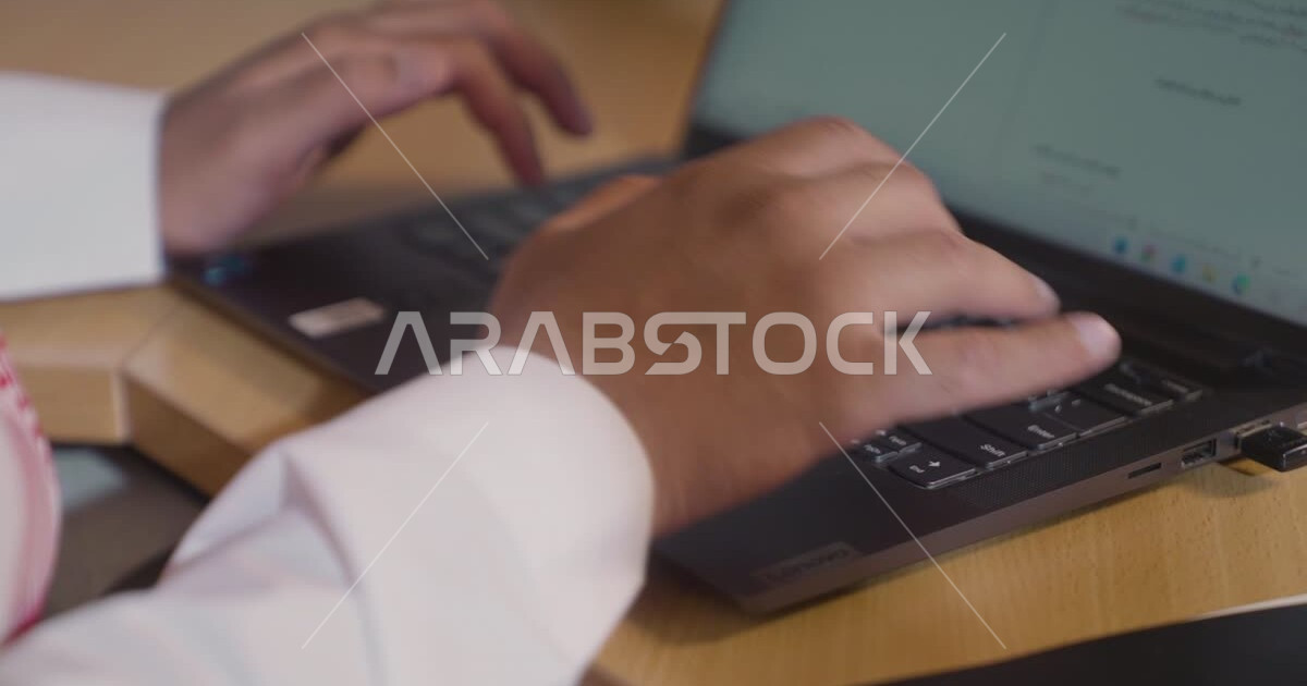 Close-up of a Saudi Arabian Gulf man using a laptop computer, doing ...