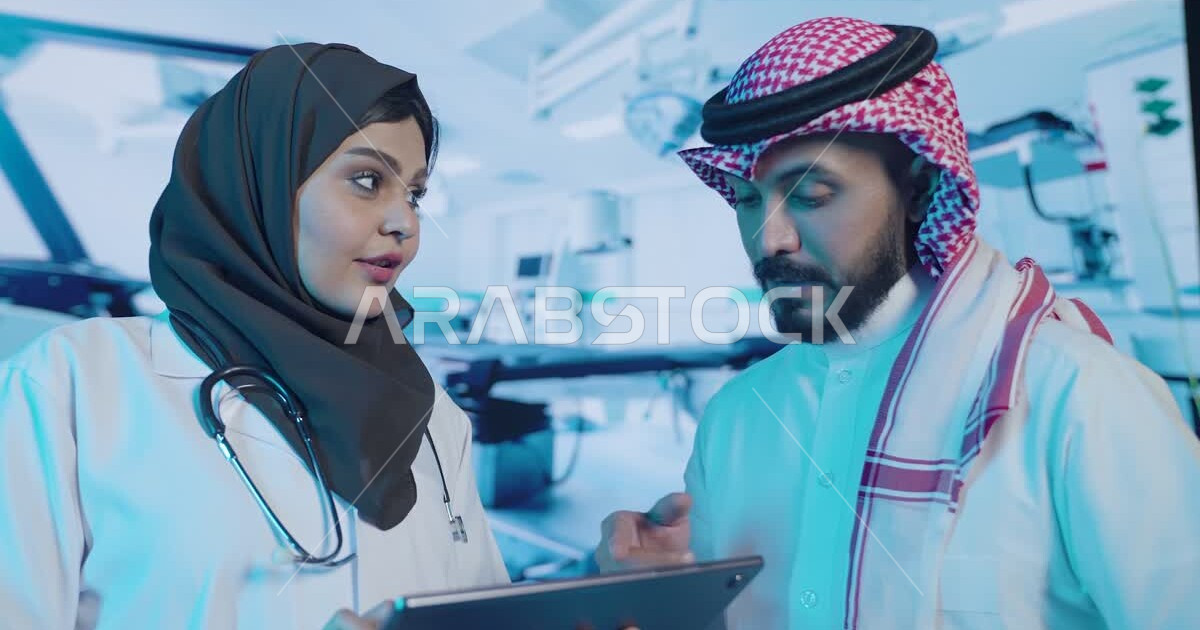 A Gulf Saudi Arabian female doctor and man using a portable tablet, the ...