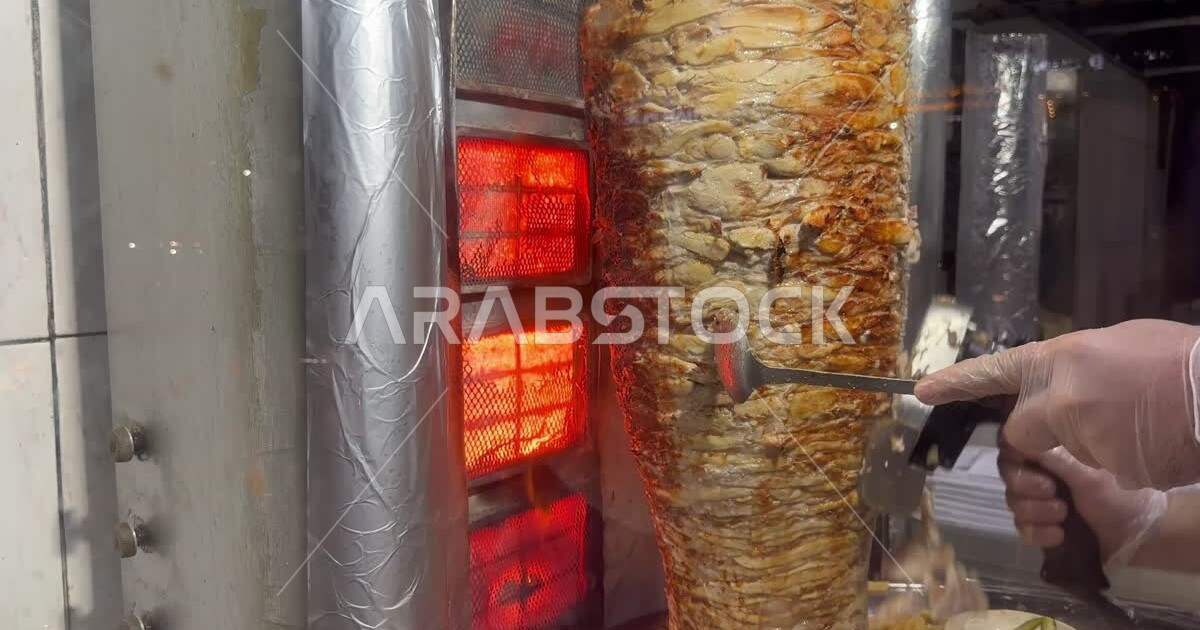 Close-up of a chef cutting shawarma, rotating a shawarma skewer on a ...