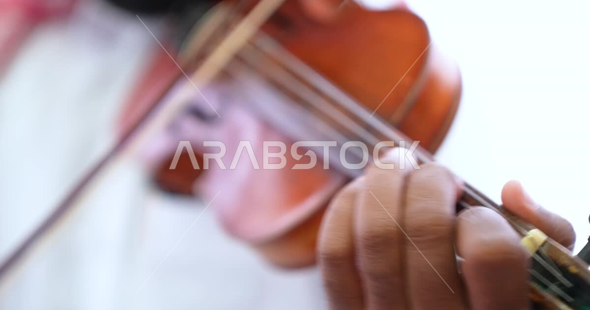 Close-up of a Saudi Arabian Gulf man, an artist playing the violin ...