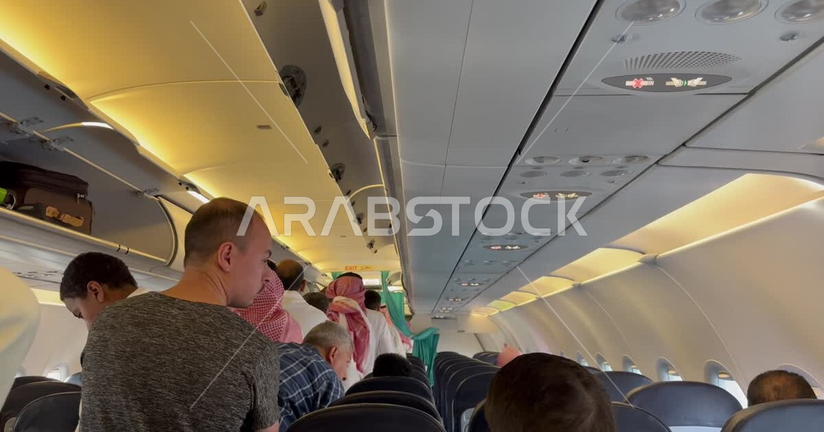 Close-up of pilgrims and Umrah performers while riding on the plane ...