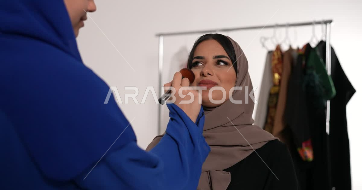 A Saudi Arab Gulf woman beautifying a modern model and models, a studio ...