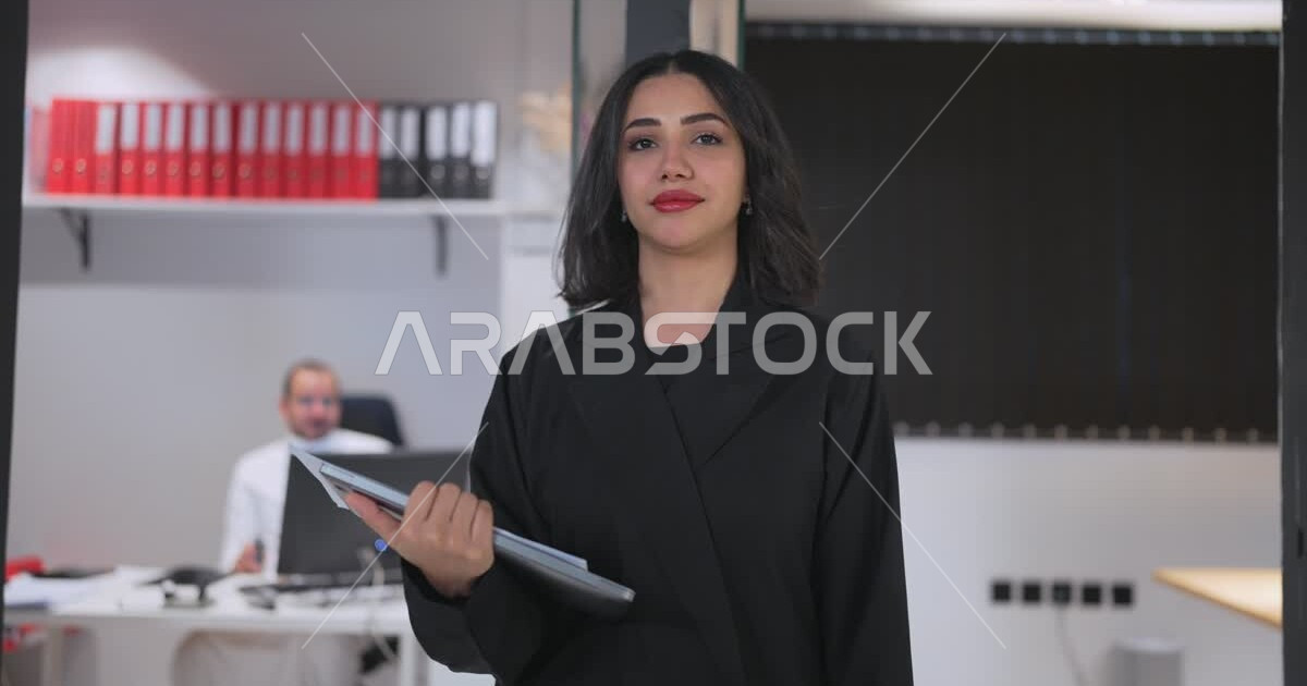 Managing daily work tasks, a Saudi Arabian Gulf businesswoman holding a ...