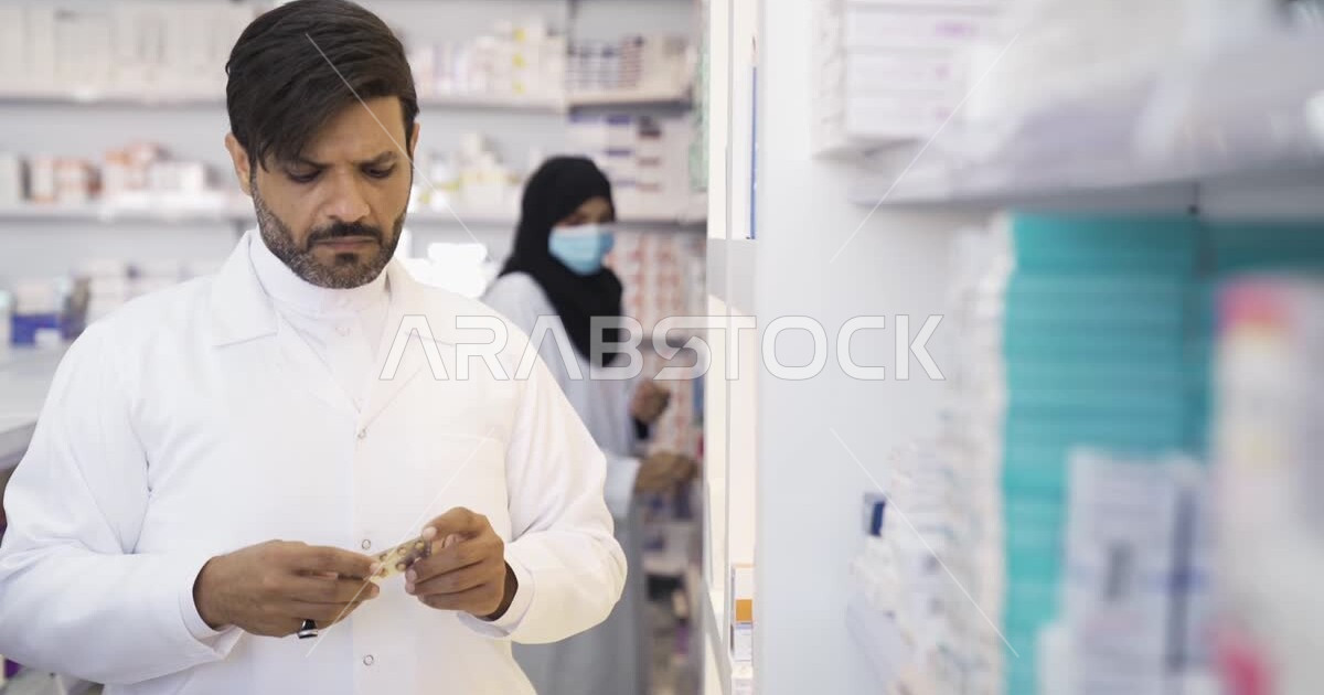 A man is a Saudi Arabian Gulf pharmacist holding medicine in his hand ...