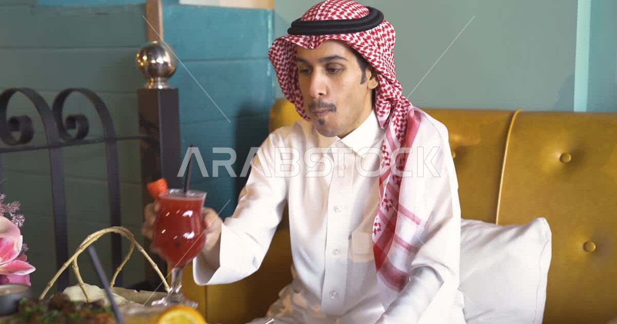 A Saudi Arabian Gulf man sitting at the dining table and drinking ...