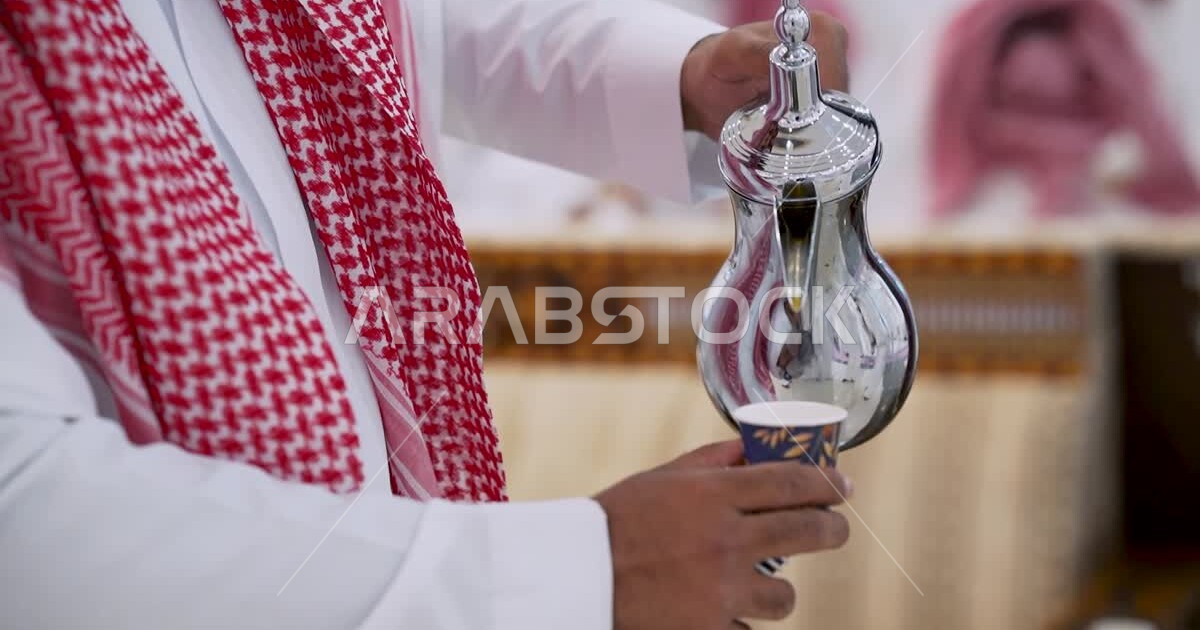 Pouring Arabic coffee, a close-up of a Saudi Arabian Gulf man who wears ...