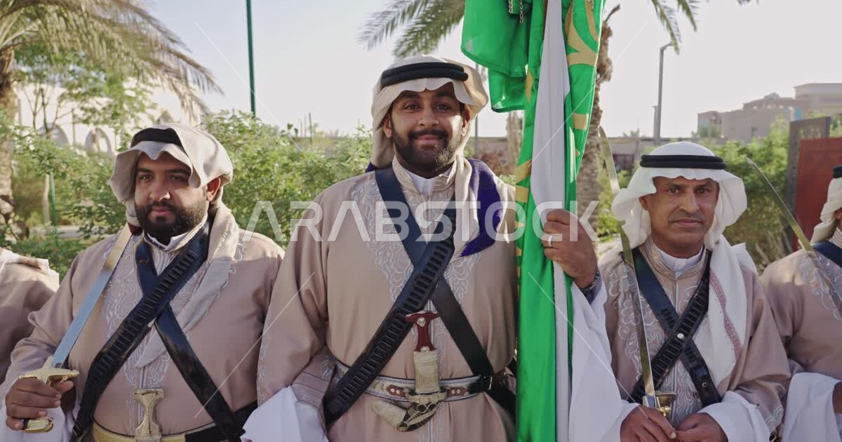 Close-up of a group of Saudi Gulf Arab men carrying swords and wearing ...