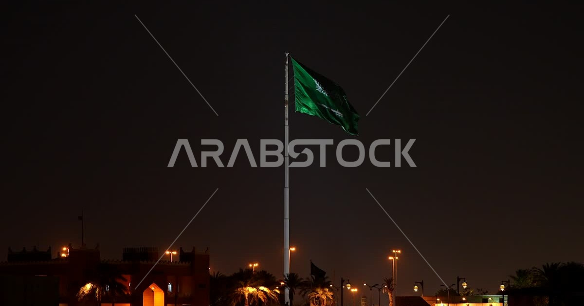 The flag of the Kingdom of Saudi Arabia flutters in the sky of the city ...