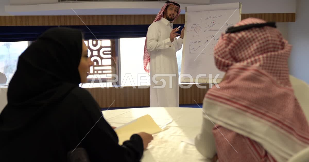 A Saudi Arabian trainer explains to Saudi Gulf trainees on a whiteboard ...